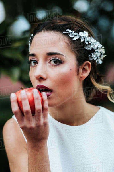 Elegant young woman biting fresh apple on wedding day in garden - Stock ...