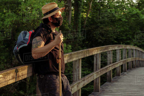 Side view of unrecognizable male wanderer in mask with backpack and ...