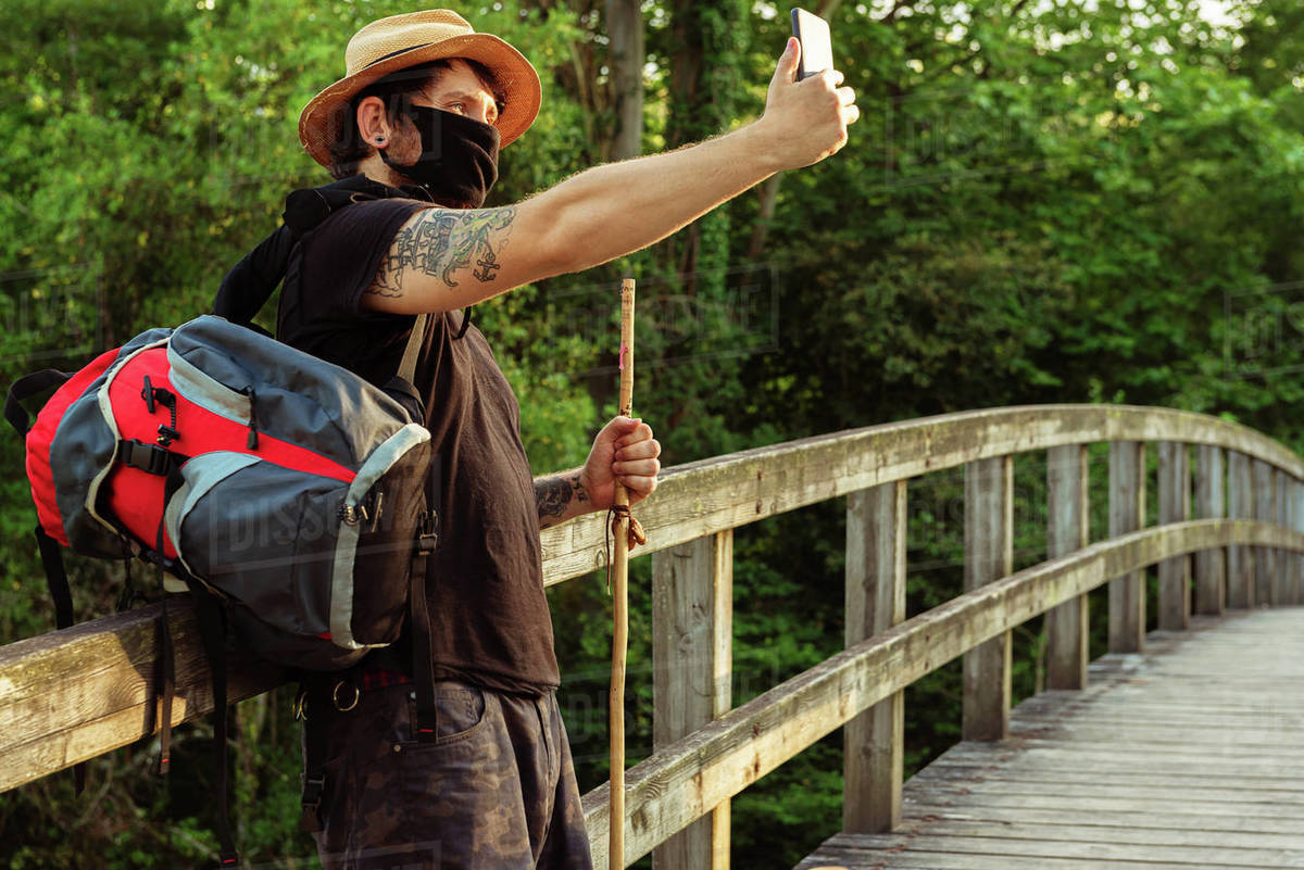 Side view of male wanderer with backpack and wooden stick standing on ...