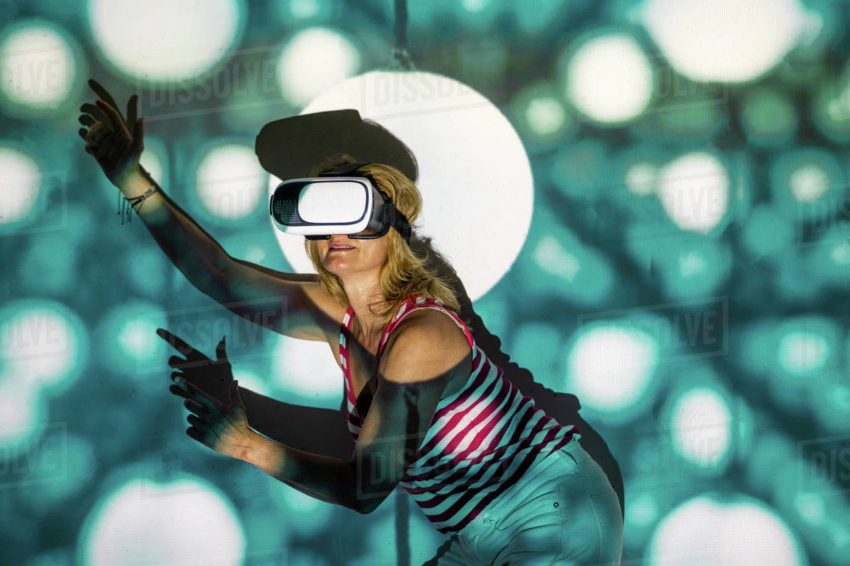 Unrecognizable young female in casual wear and VR headset getting new ...