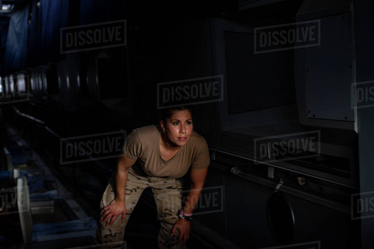 Side view of strong female soldier pointing up while looking at sky ...