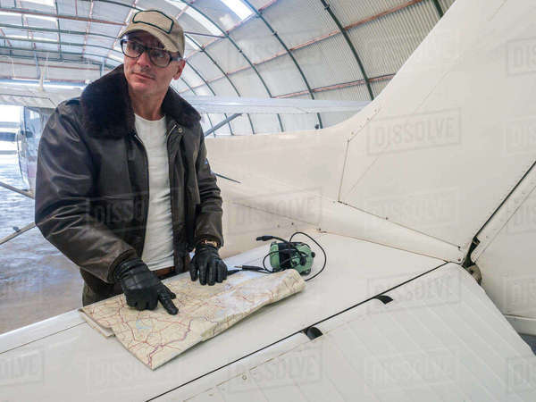 Pilot with map on small plane - Stock Photo - Dissolve