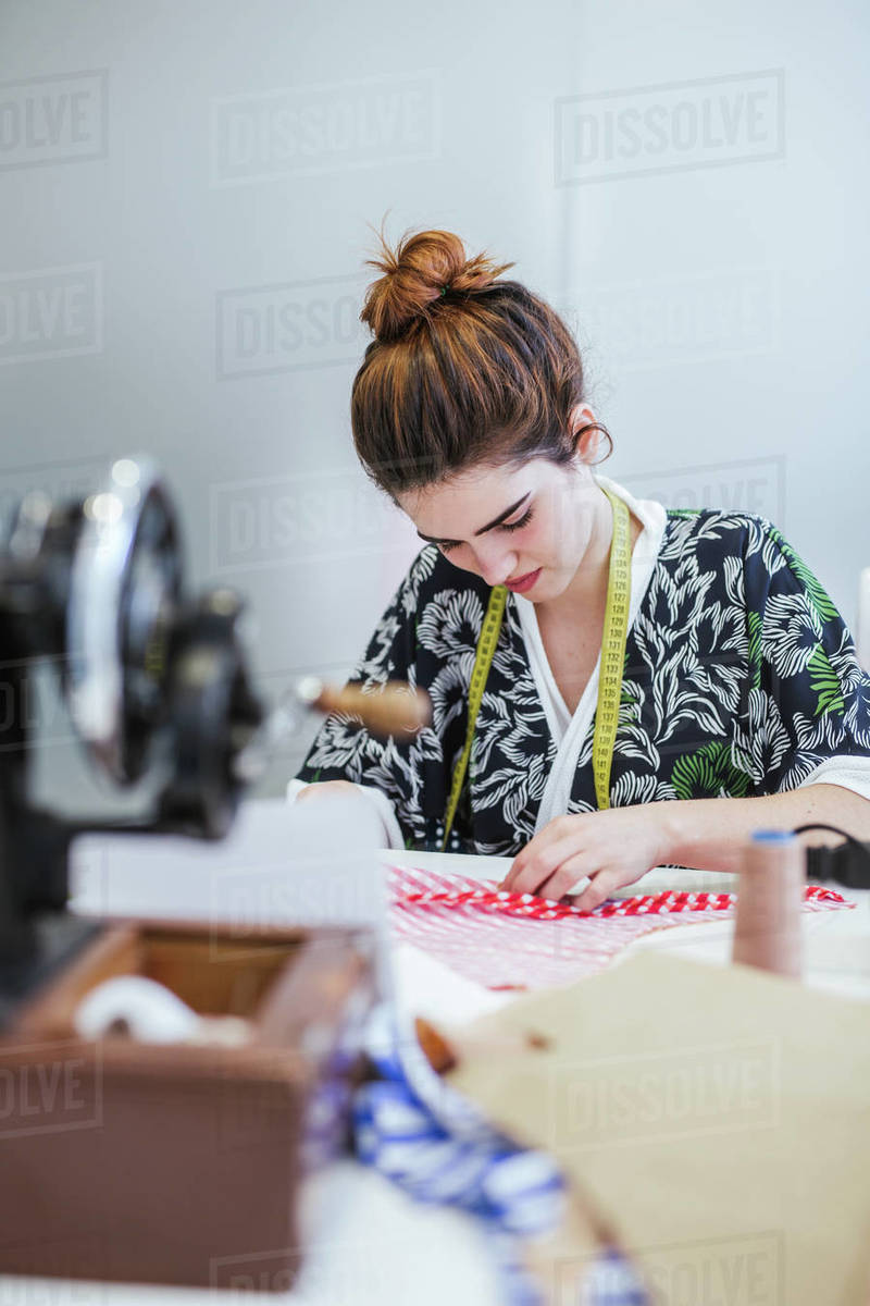 Teenage girl student practicing sewing on modern machine in cozy ...