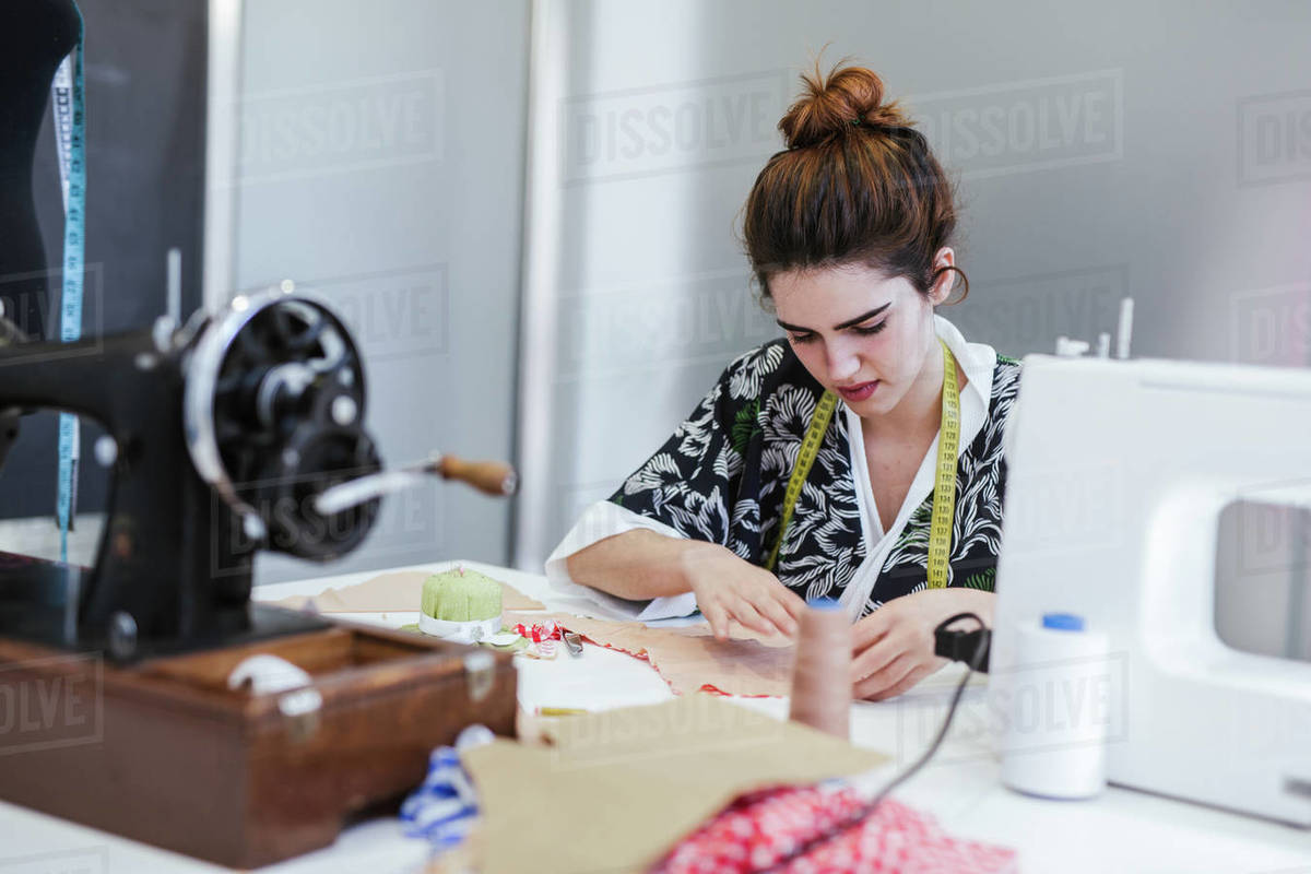 Teenage girl student practicing sewing on modern machine in cozy ...