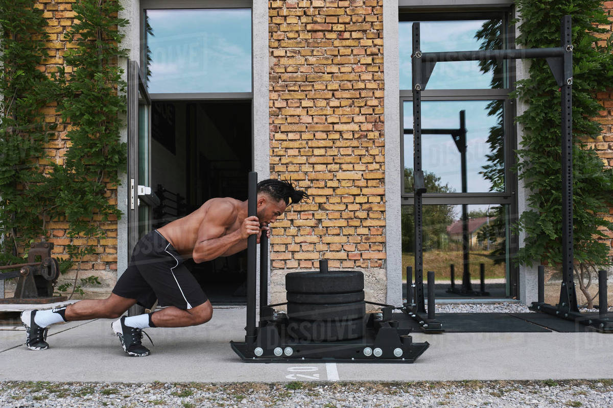 Black guy pulling weights in outdoor gym - Stock Photo - Dissolve