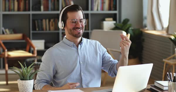 Funny happy businessman wears wireless headphones having fun listening ...