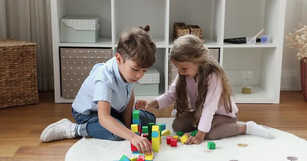 Two cute little siblings play wooden colorful bricks at home - Stock ...