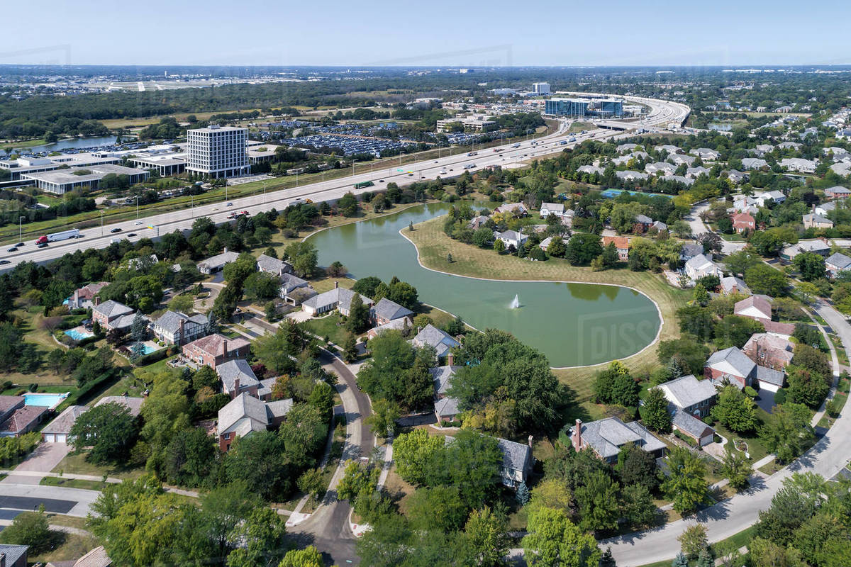 Aerial view of a neighborhood with pond beside a major highway in the ...
