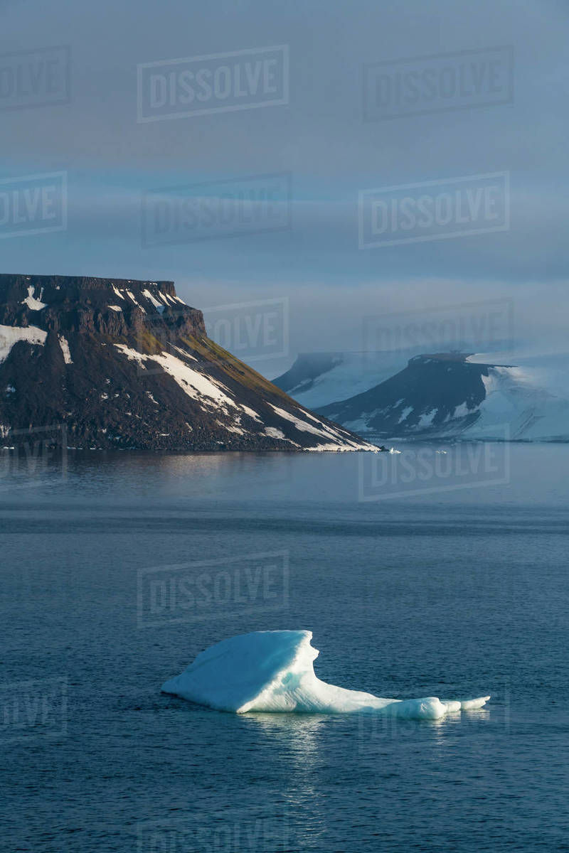 Iceberg floating in front of flat table mountains covered with ice ...