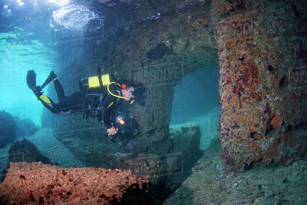 Scuba diver swimming through submerged ancient Roman ruins, Dragonara ...
