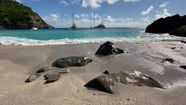 Turquoise sea swirls around beautiful beach rocks, lapping waves ...