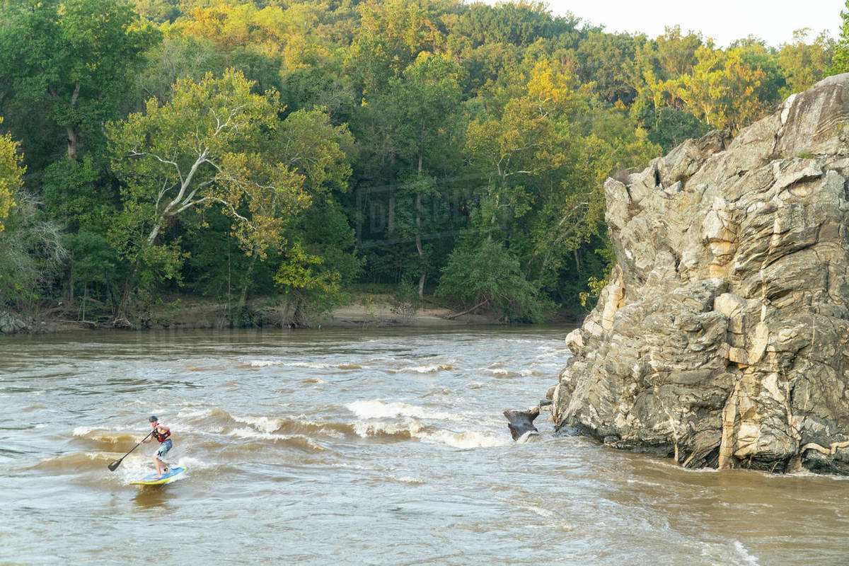 Ian Brown stand up paddle surfs a whitewater wave on the Potomac River ...