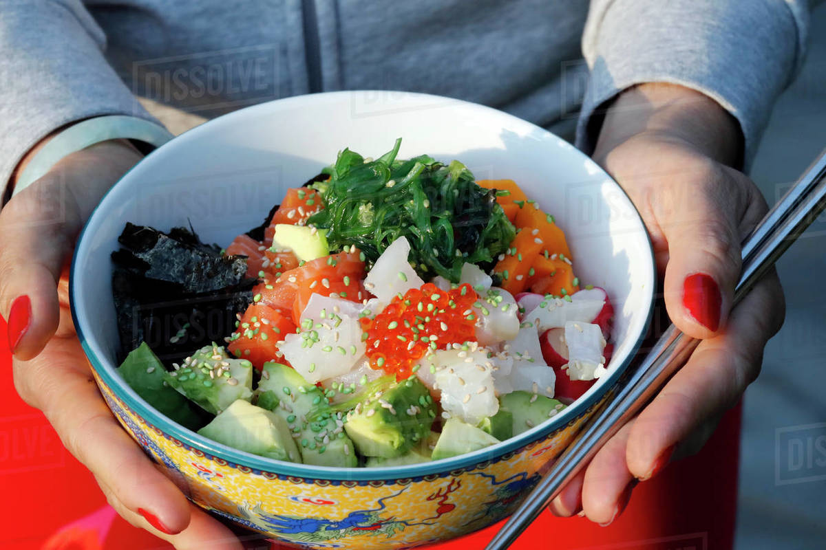 Asian cuisine, fish poke bowl with seaweed, avocado, cucumber, radish ...