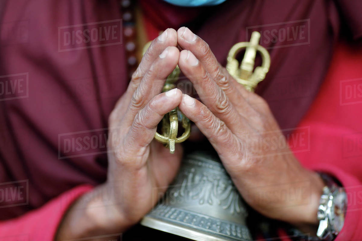 Buddhist monk (lama) in traditional robes holding ritual attributes of ...