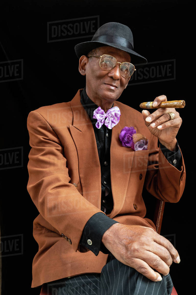 Man seated dressed as 1950s dandy or gangster with fedora hat and big ...