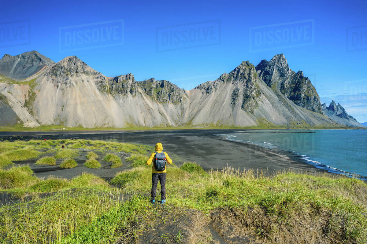 Man hiker with backpack at black sand dunes on the Stokksnes headland ...