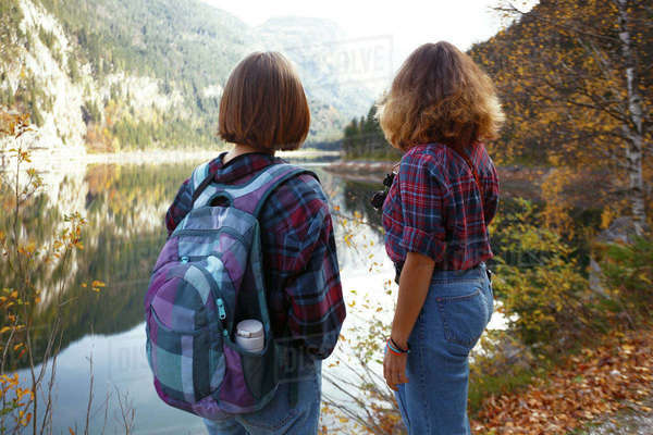 mountain trip. two happy girls on the background of a mountain lake and ...