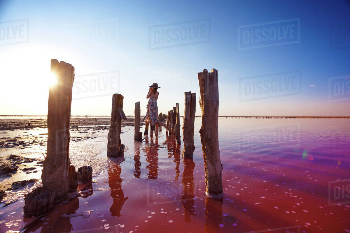 girl posing at sunset on the famous pink salt lake. reflection in the ...
