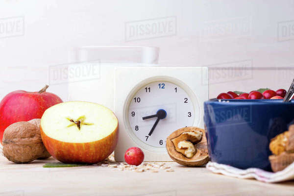 healthy breakfast - clock, milk, oatmeal, cranberries, nuts, apples on ...