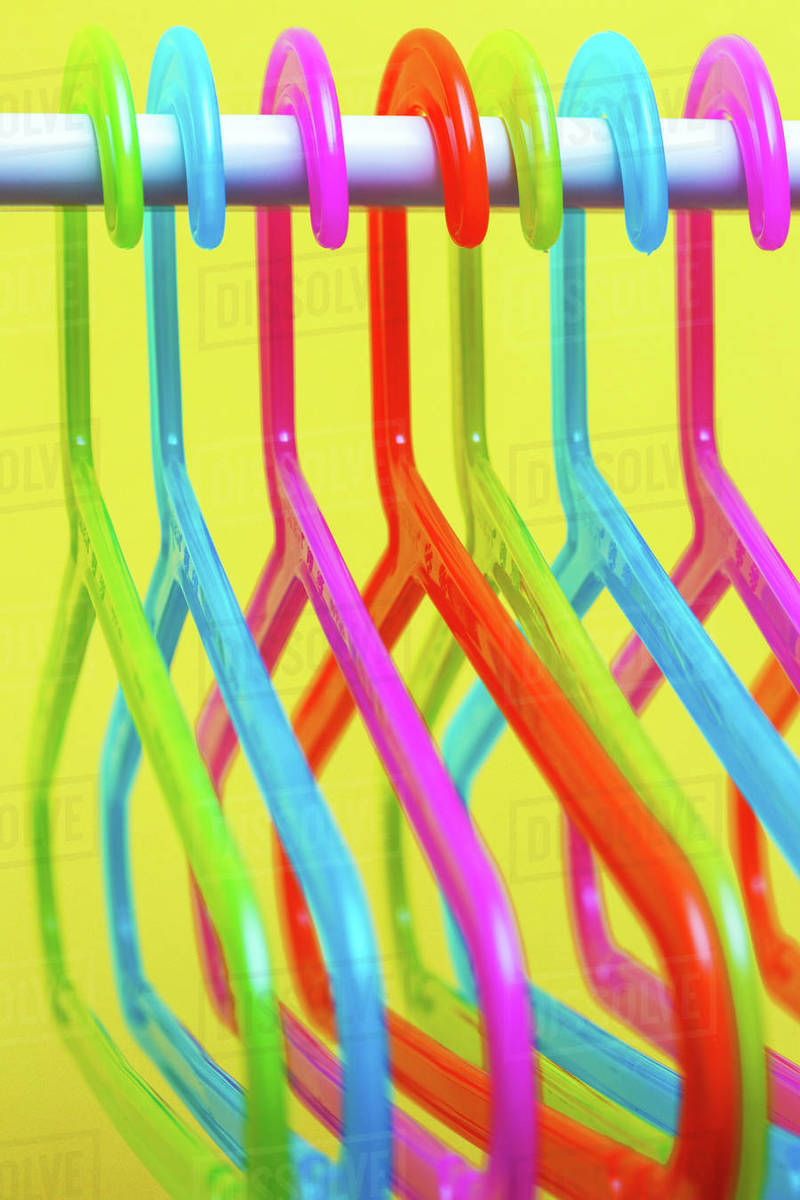 Multicolored hangers on yellow background with small depth of field ...