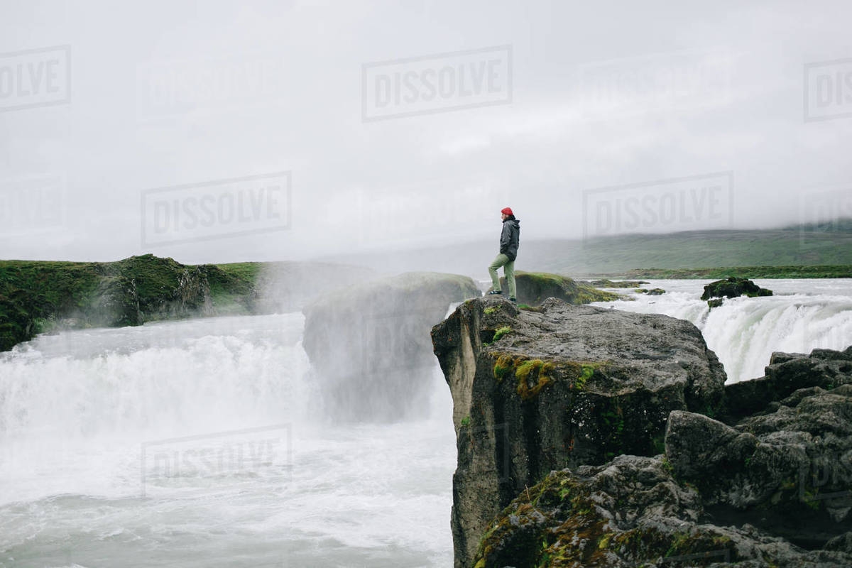 Epic cinematic shot of young man on edge of waterfall cliff - Royalty ...