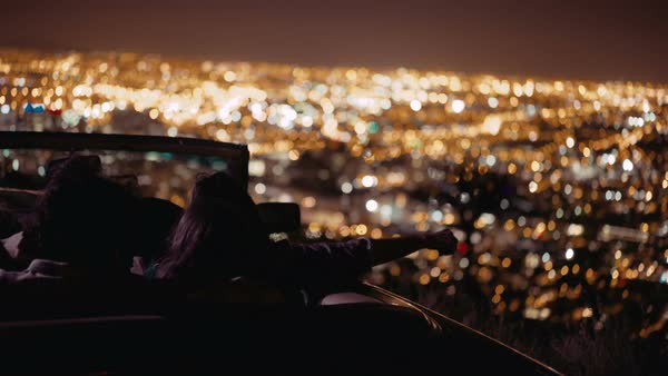 Back view of a group of friends sitting in a convertible a car and ...
