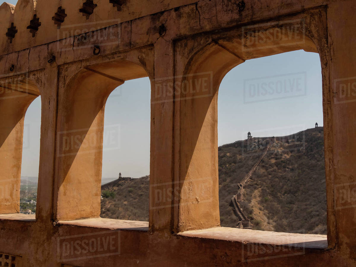 towers and fort walls on a hill frameed amber fort arches in jaipur ...