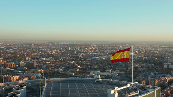 Fly around Spanish flag waving in wind on rooftop of business ...