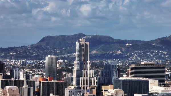 Zoomed shot of high rise office towers in city and Hollywood Sign in ...