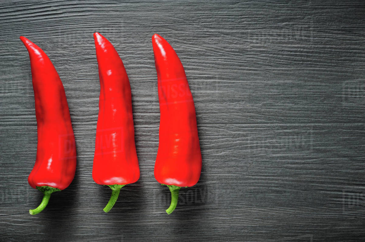 Three ripe sweet red Kapia peppers on dark shale stone background ...