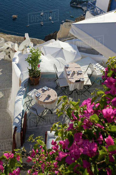 Greece, Santorini, Thira, Oia. Looking down on patio tables set for ...