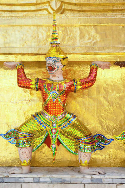 Bangkok, Thailand - A statue is standing and holding a heavy, golden ...