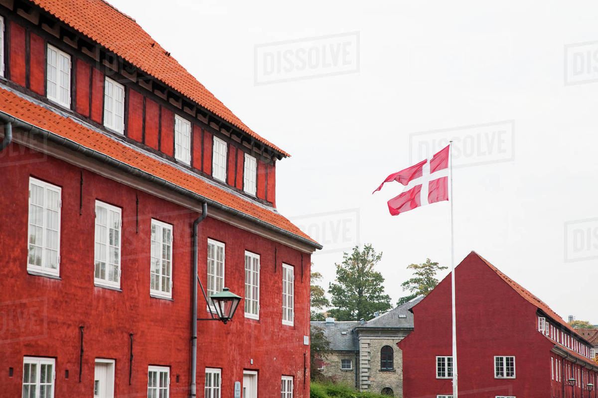 Copenhagen, Denmark - A Danish flag is flying in front of red military ...