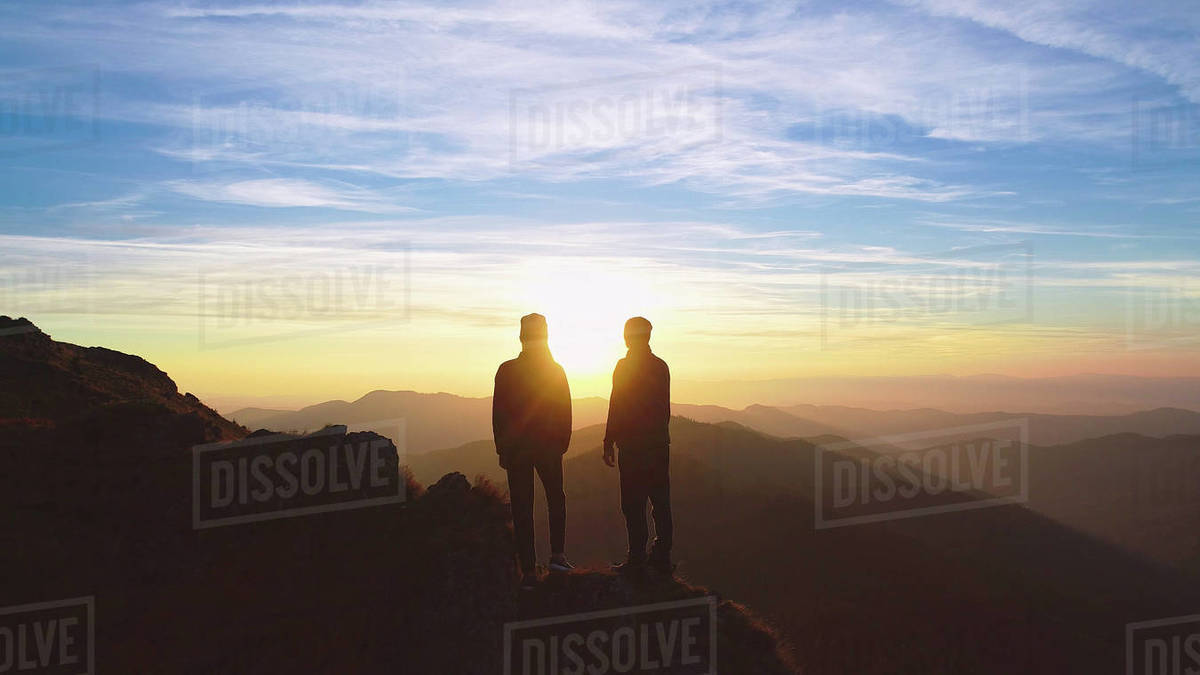 The couple standing on the mountain on the beautiful sunrise background ...