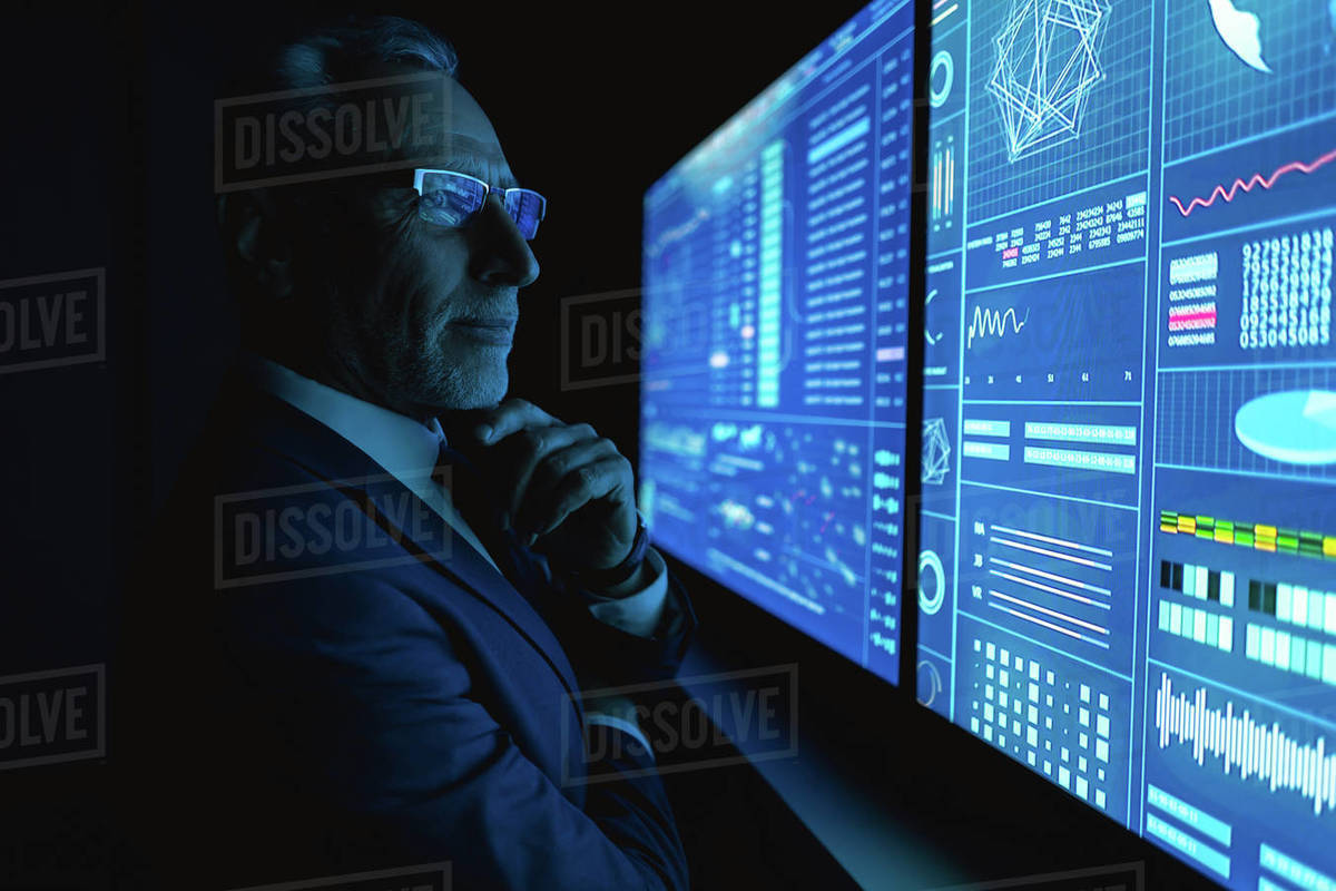 The old businessman standing near the big blue screen with graphics ...