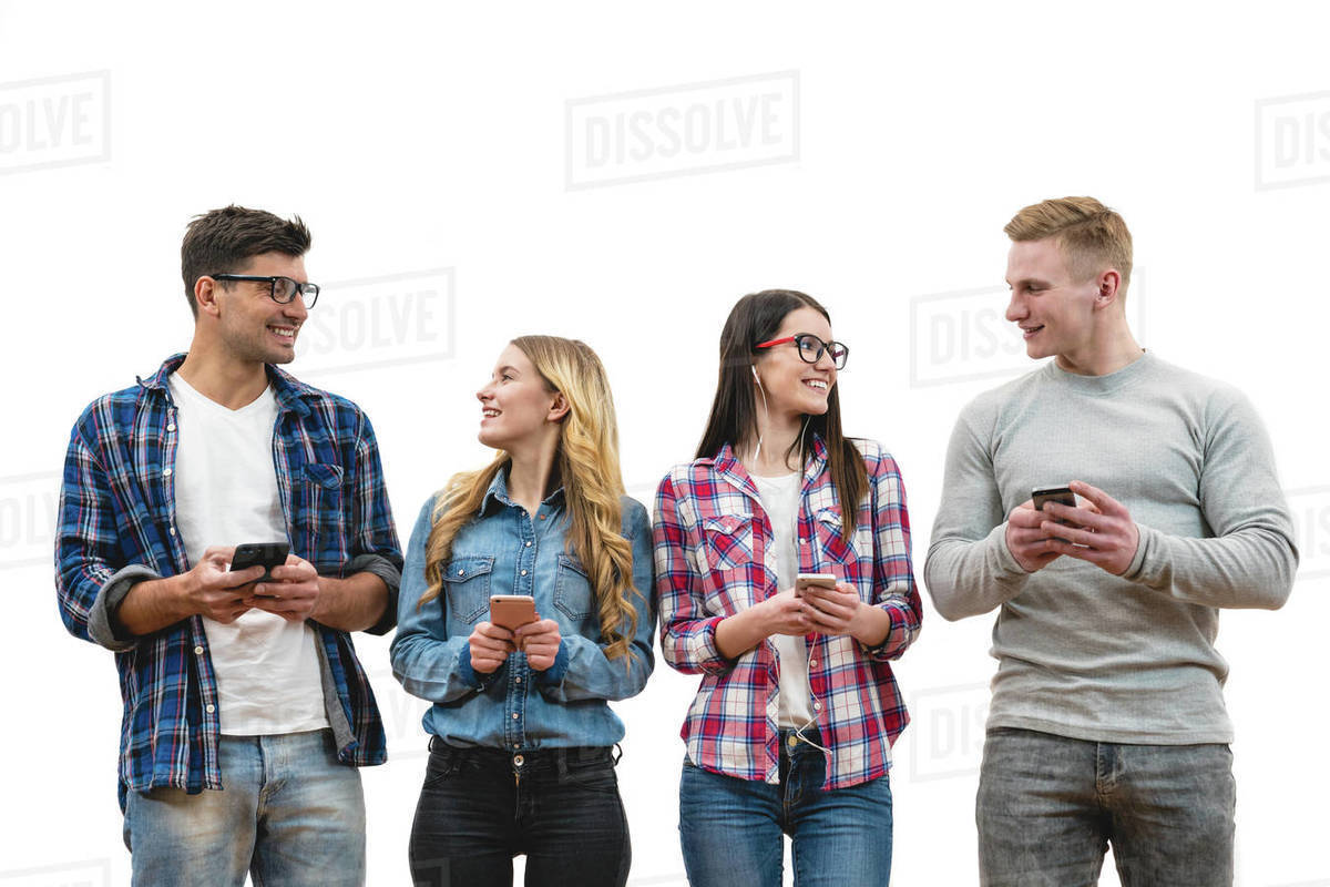 The four happy people with phones stand on the white wall background ...