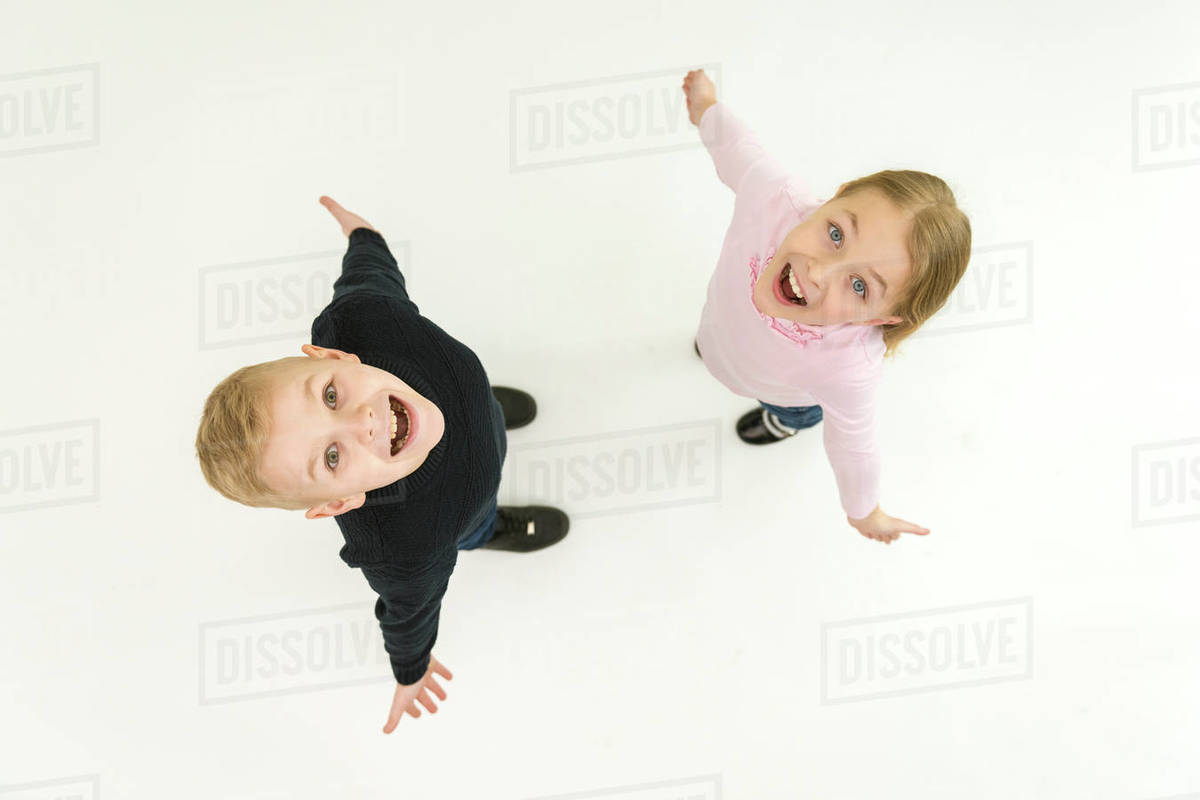 The two laugh children stand on the white background. View from above ...