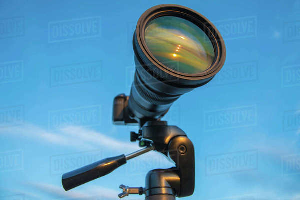 The camera with a telephoto lens on the blue sky background - Royalty ...