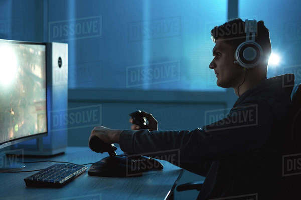 The guy gamer with headphones playing video games in the dark room ...