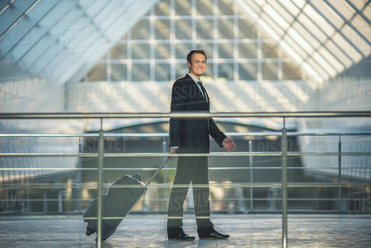 The happy man walk with a suitcase in the business center - Royalty ...