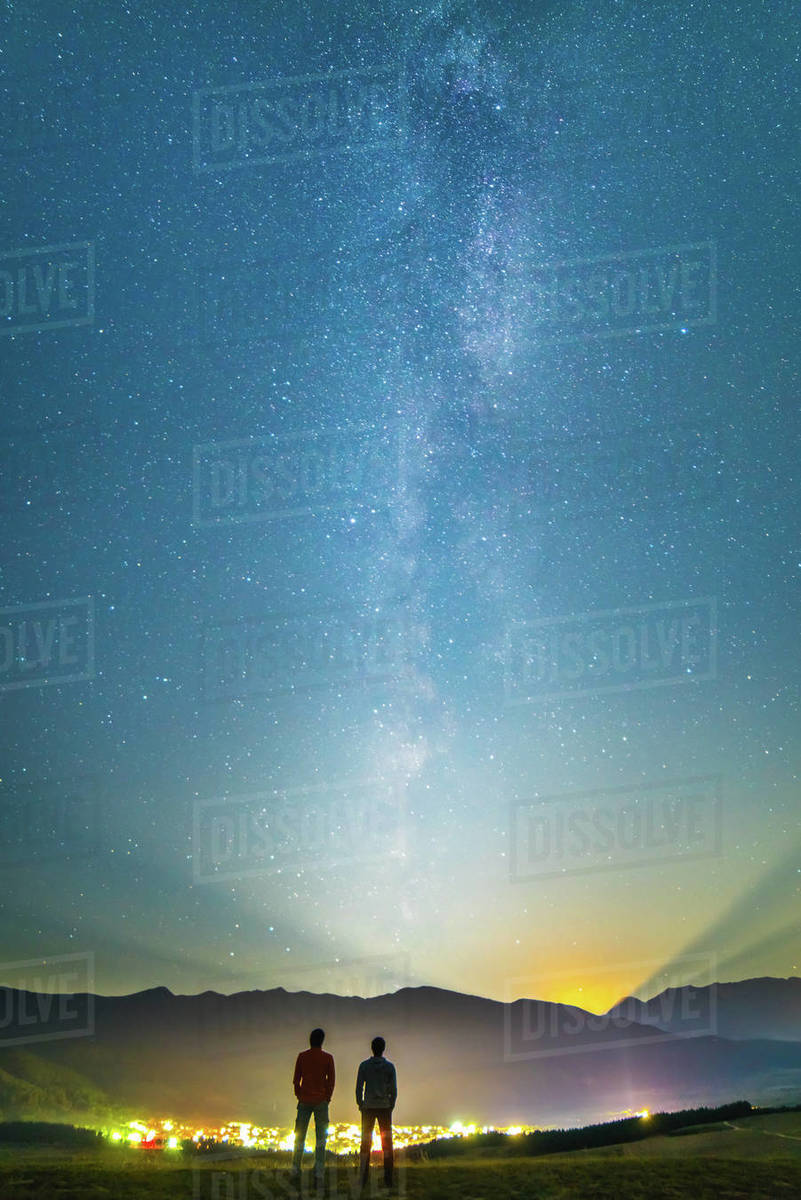 The two friends stand on the background of the starry sky. night time ...