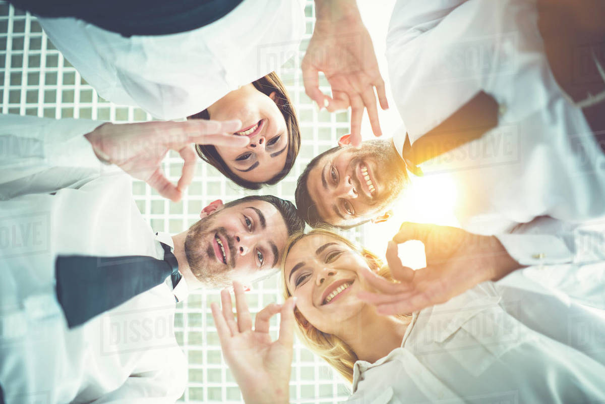 The four happy people gesture to the camera on the sunny background ...