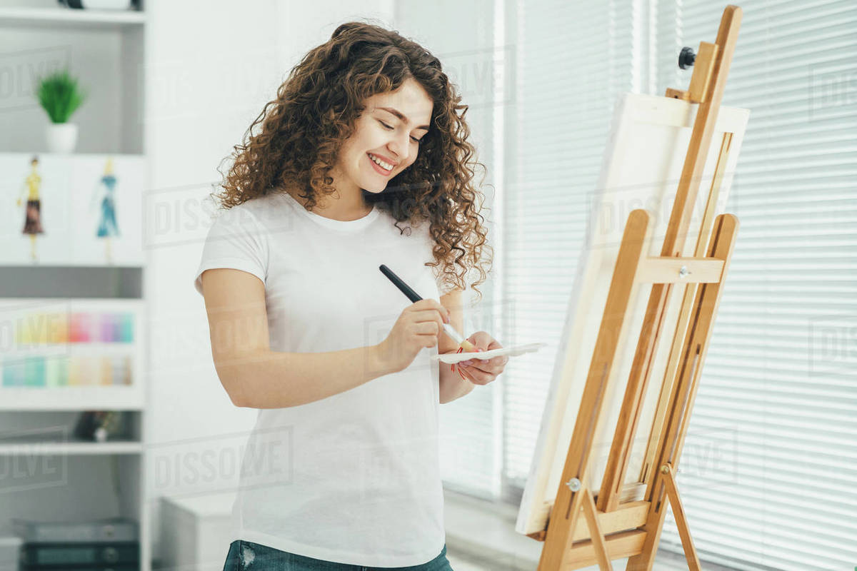 The happy artist painting a picture on the easel - Stock Photo - Dissolve