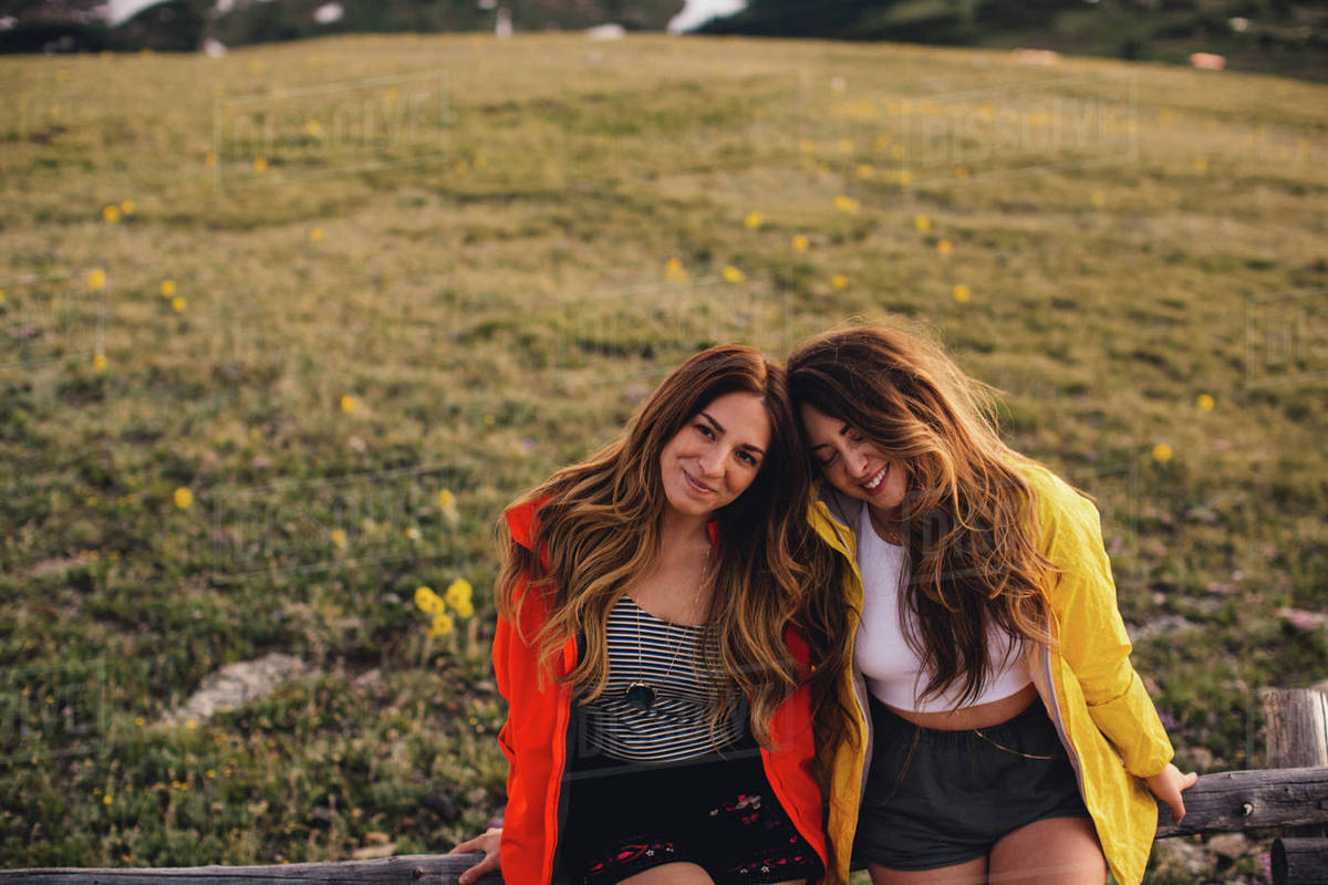 Friends sitting side by side looking at camera smiling, Rocky Mountain ...