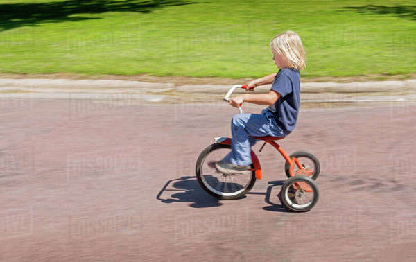 Side view of boy riding tricycle - Royalty-free Stock Photo | Dissolve