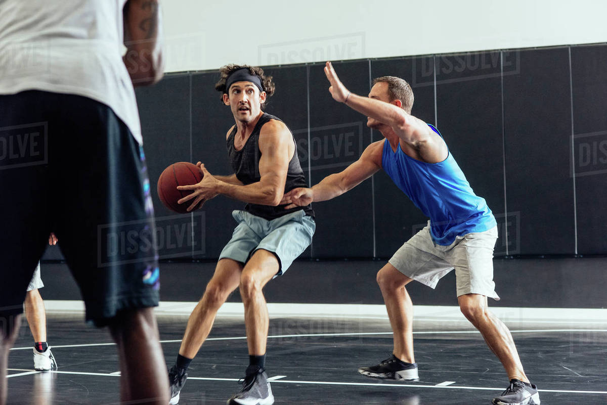 Male basketball players defending ball in basketball game - Stock Photo ...