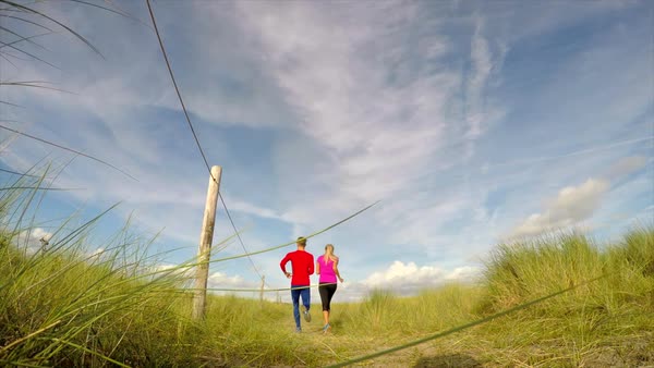 Man and woman running through grass - Stock Video Footage - Dissolve
