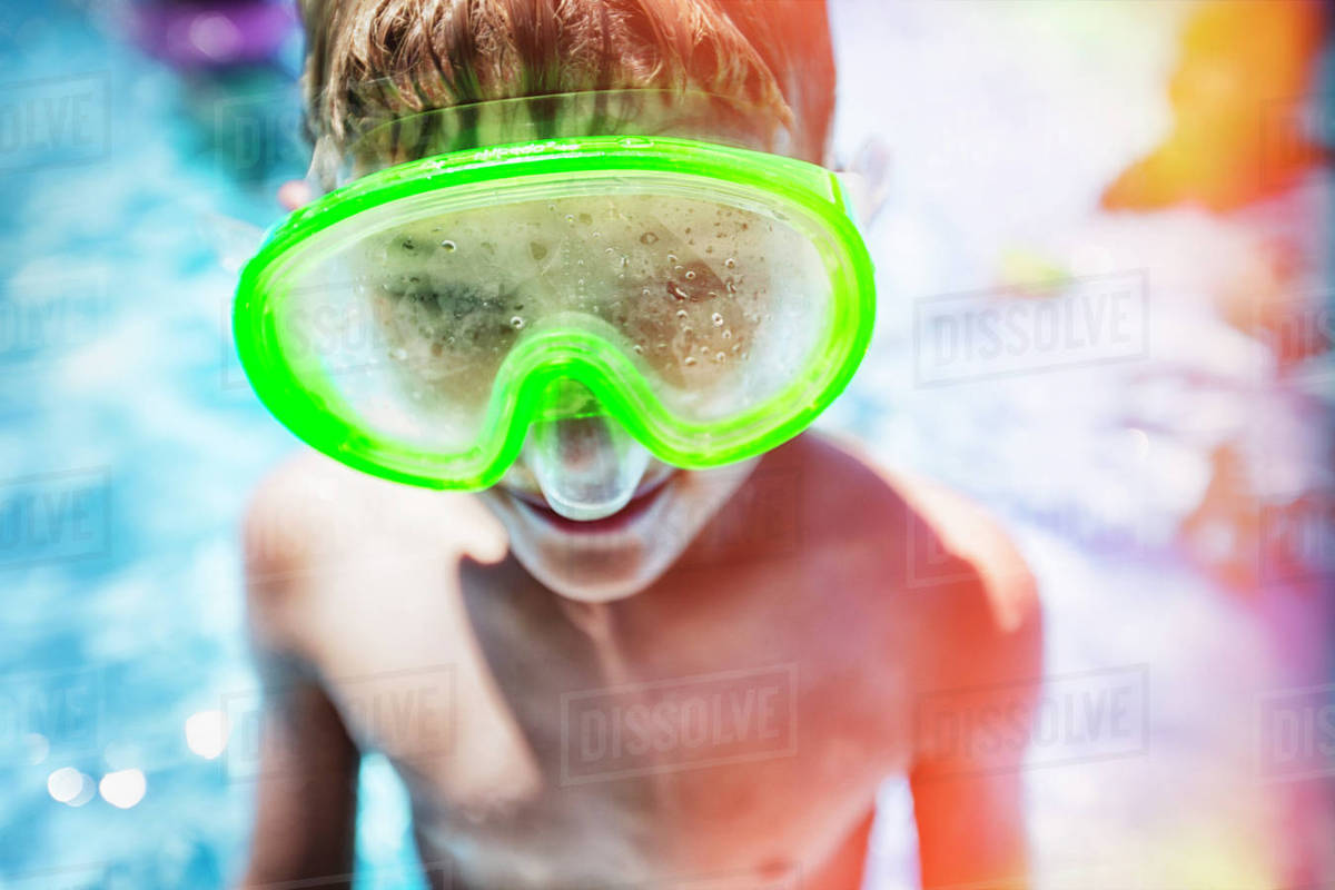 Portrait of boy in swimming pool with steamed swimming goggles ...