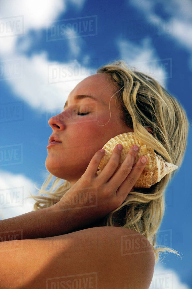 Woman listening to seashells outdoors - Royalty-free Stock Photo | Dissolve
