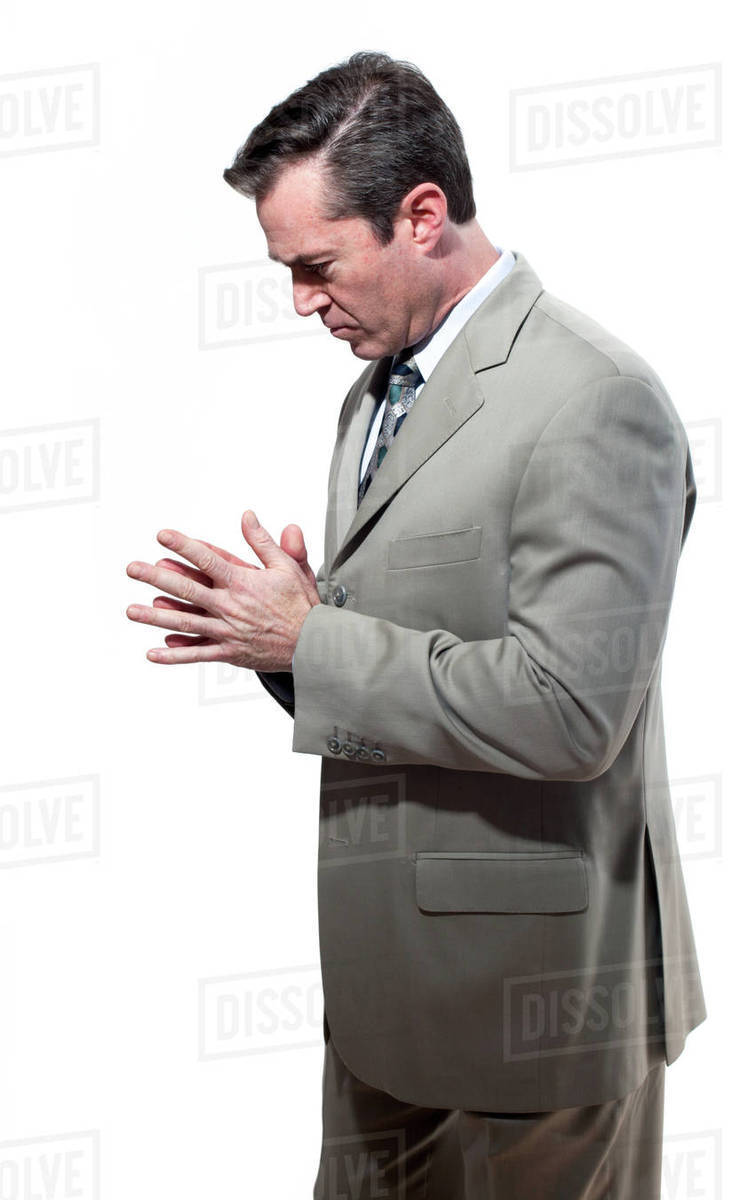 Serious looking businessman with hands together - Stock Photo - Dissolve
